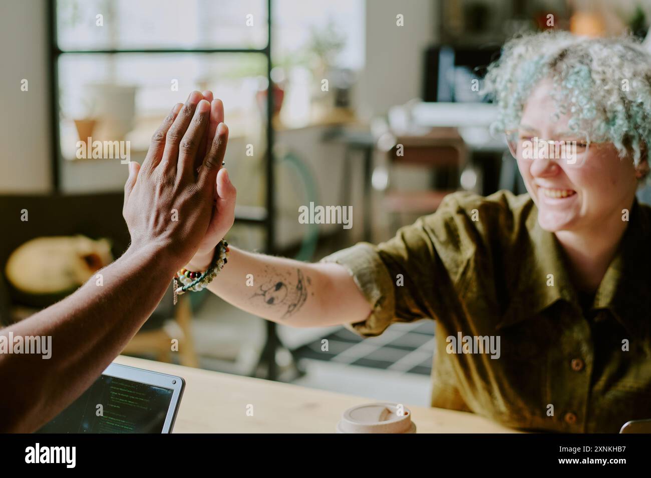 Young Caucasian female programmer with tattoo on arm doing high five ...