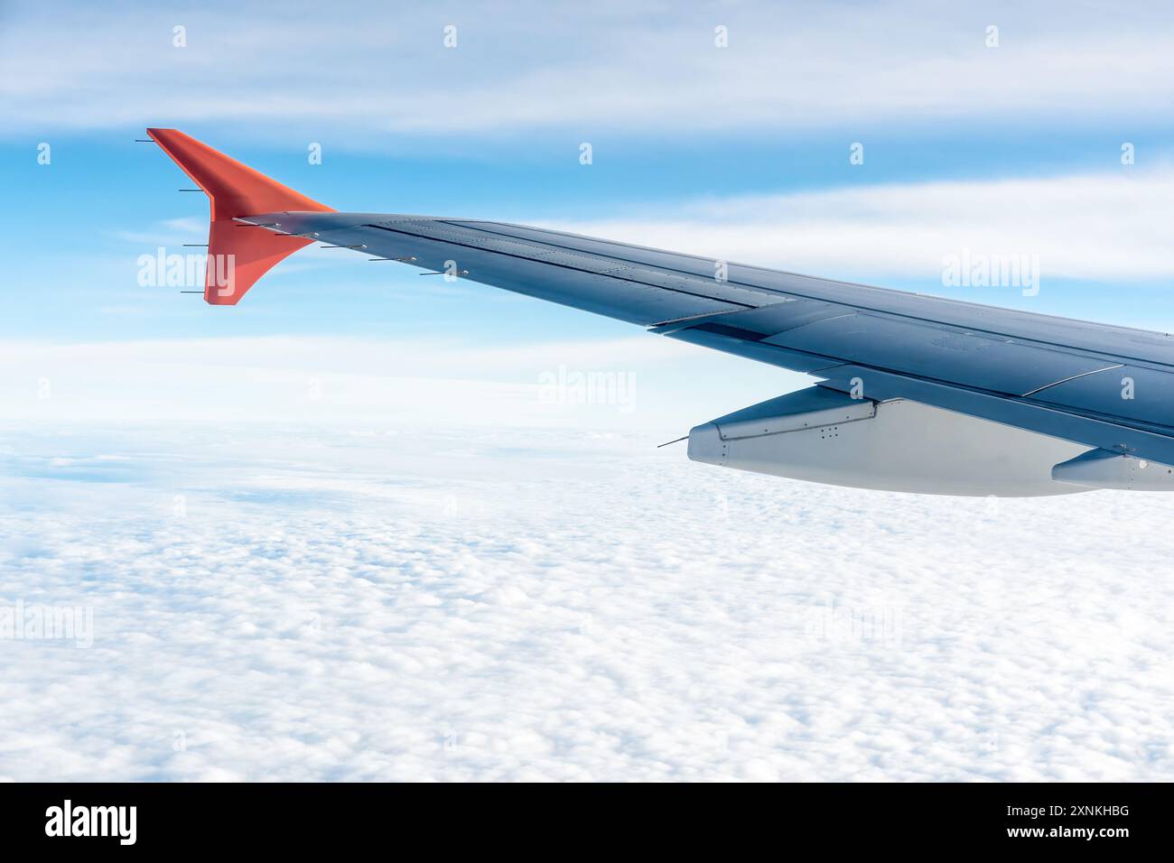 Long airplane wing with red fin high up in the sky. View from plane ...