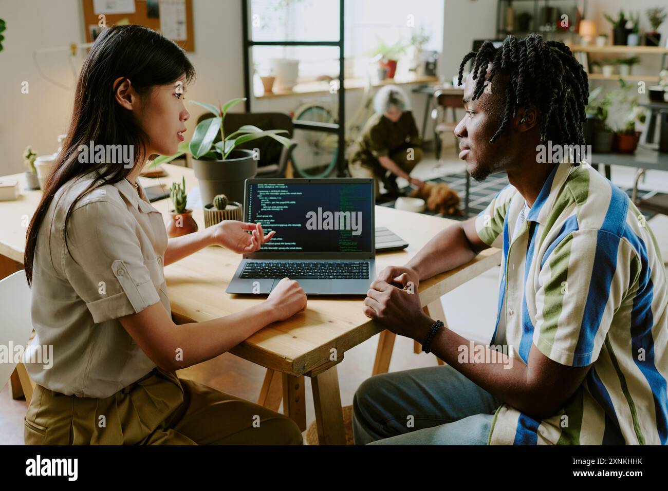 Young Black male and Asian female developers discussing code while ...