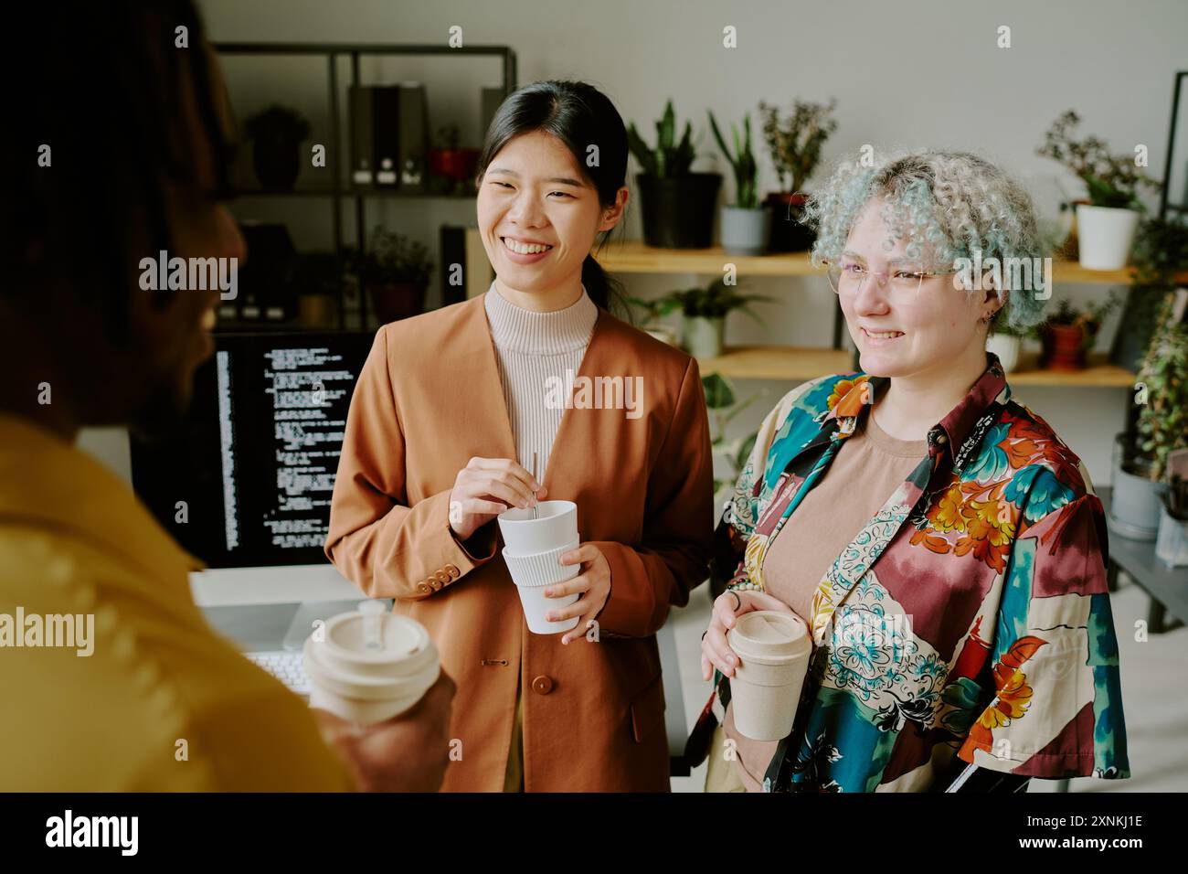 Group of three diverse gen Z colleagues holding reusable cups having ...
