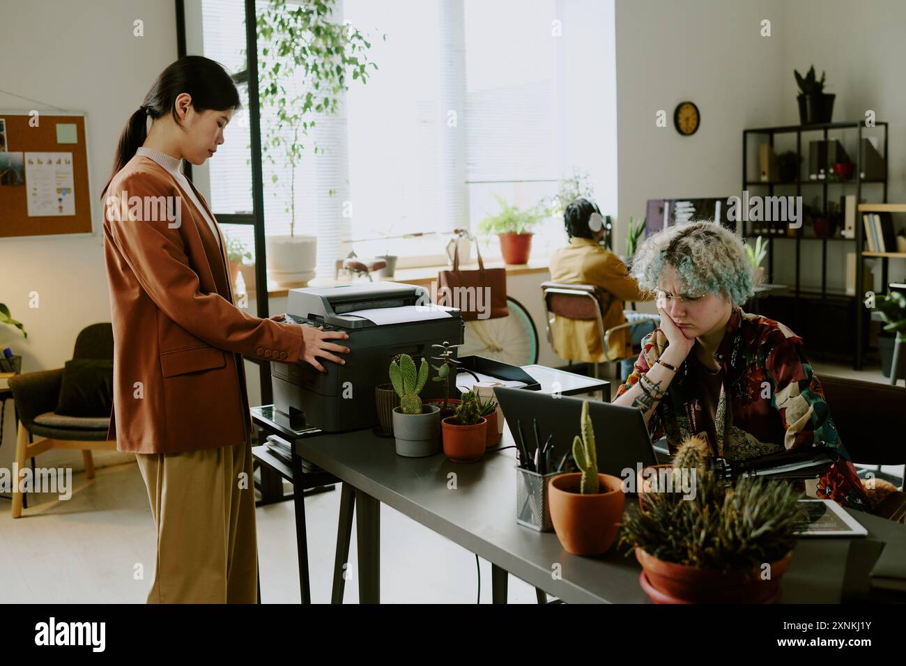 Young Asian woman printing documents while her Caucasian colleague ...