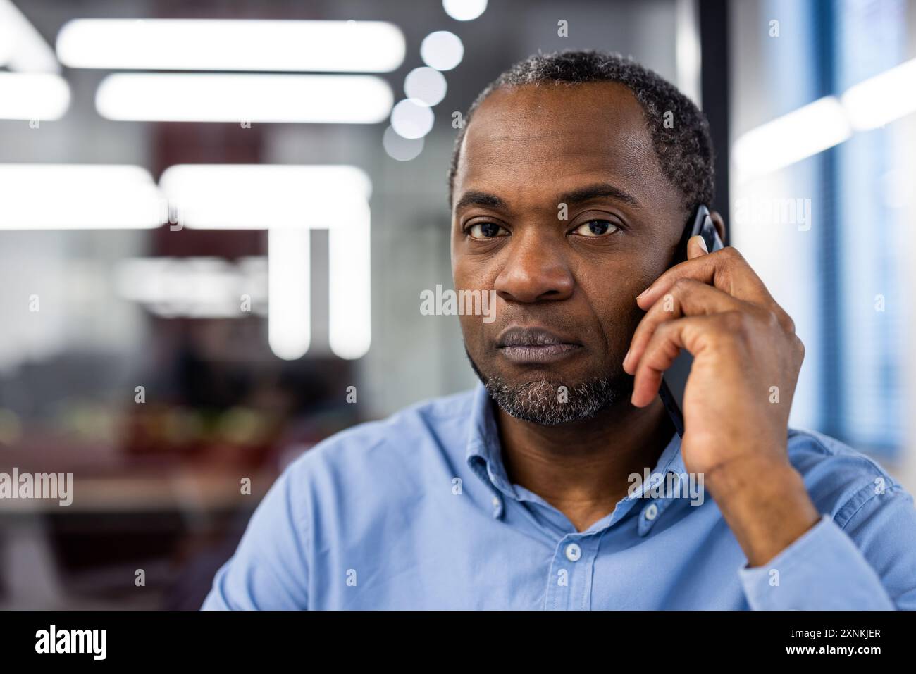 Mature African American office worker talking on phone inside modern ...