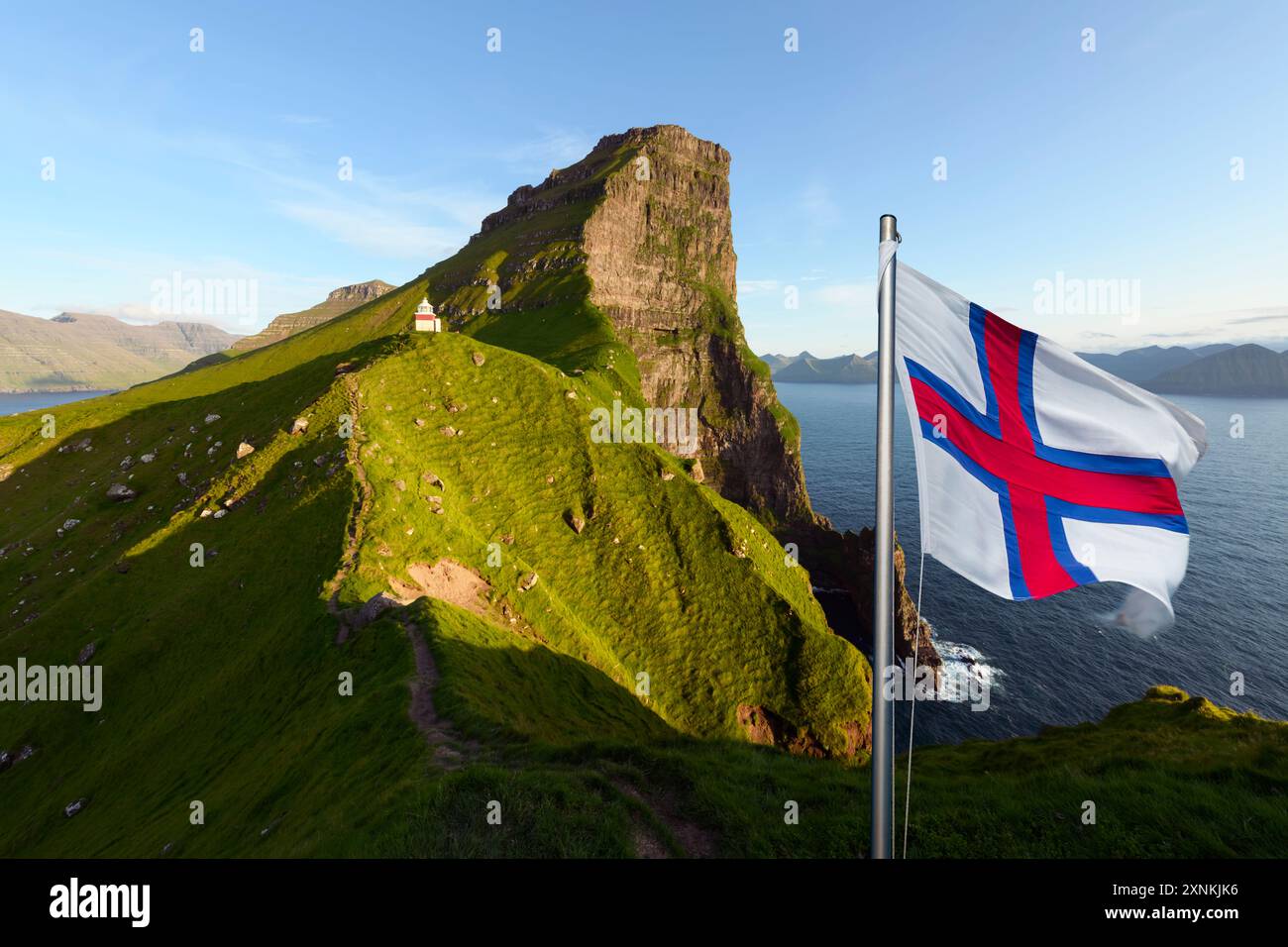 National Faroese flag waving against a background of Kallur lighthouse ...