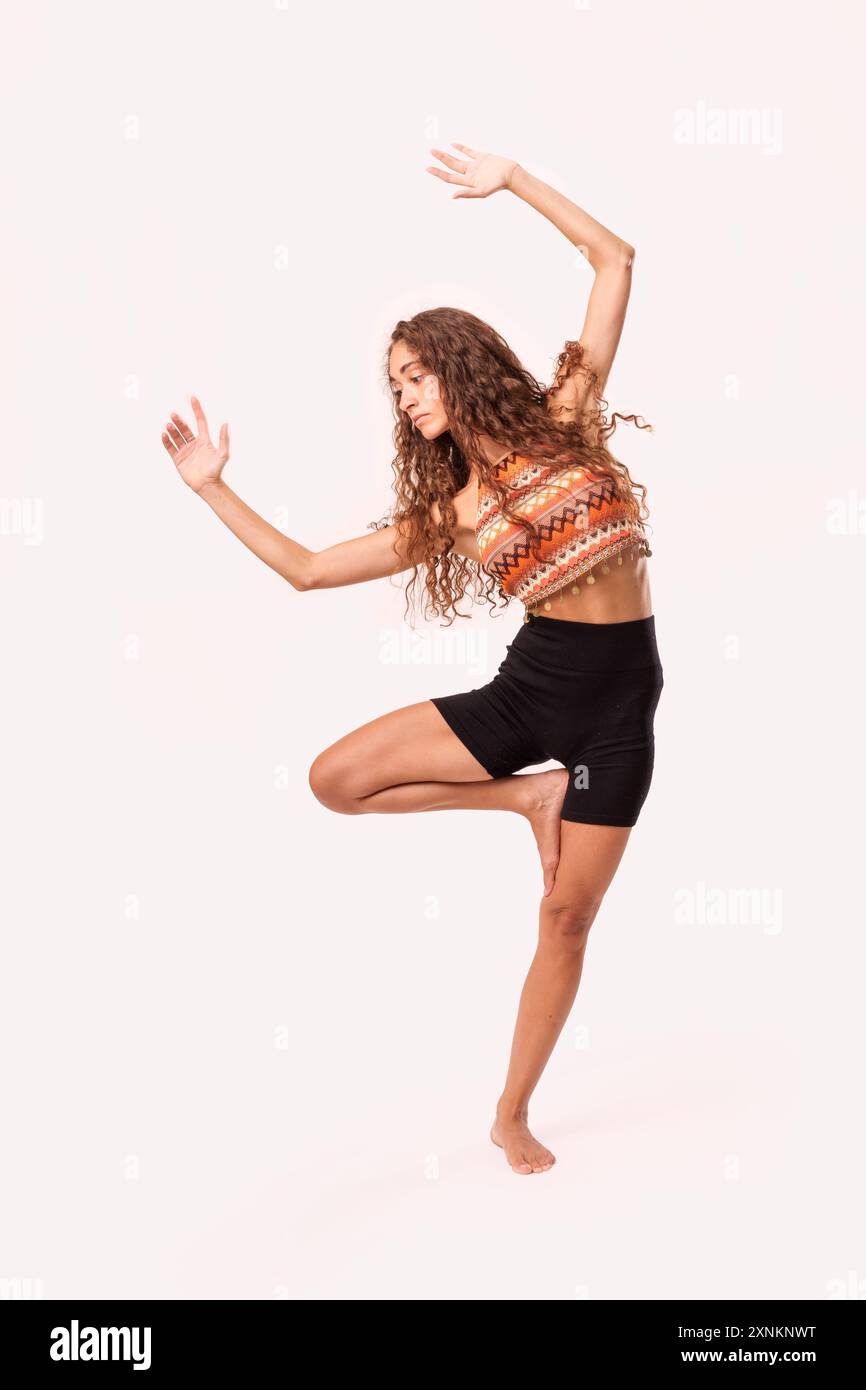 Young woman performing a challenging yoga balance pose, wearing a ...