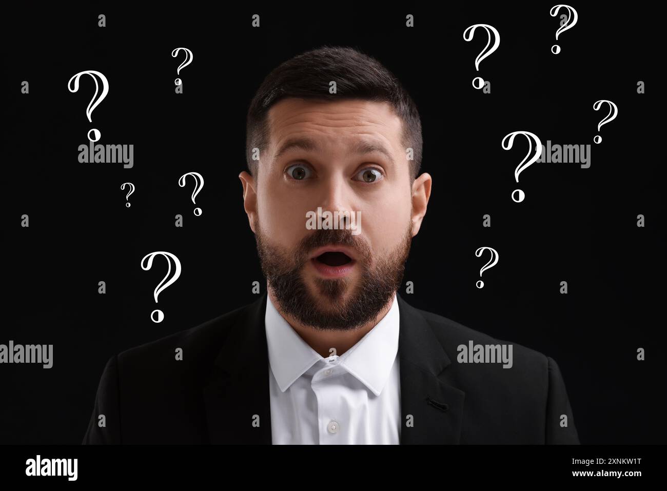 Shocked man and question marks on black background Stock Photo - Alamy