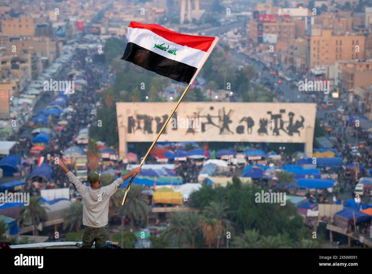 A man holds Iraqi flag near Tahrir Square in Baghdad during anti ...