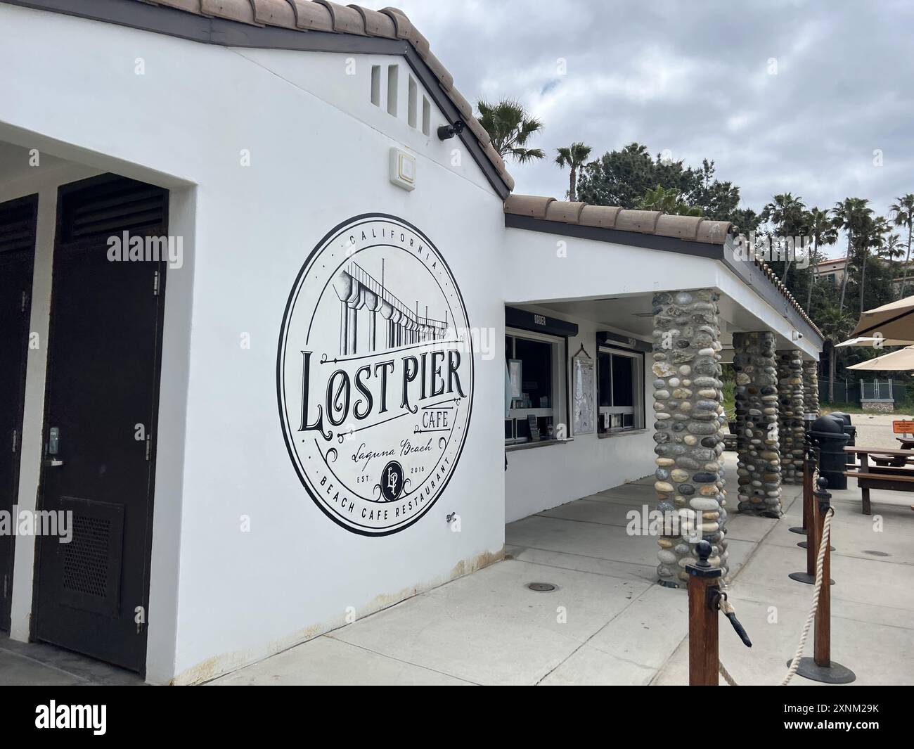 Exterior view of Lost Pier Cafe with logo sign, beachfront dining area ...