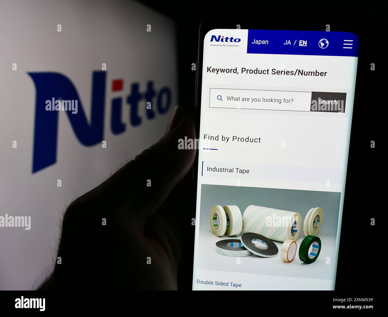 Person holding cellphone with webpage of Japanese chemical company ...