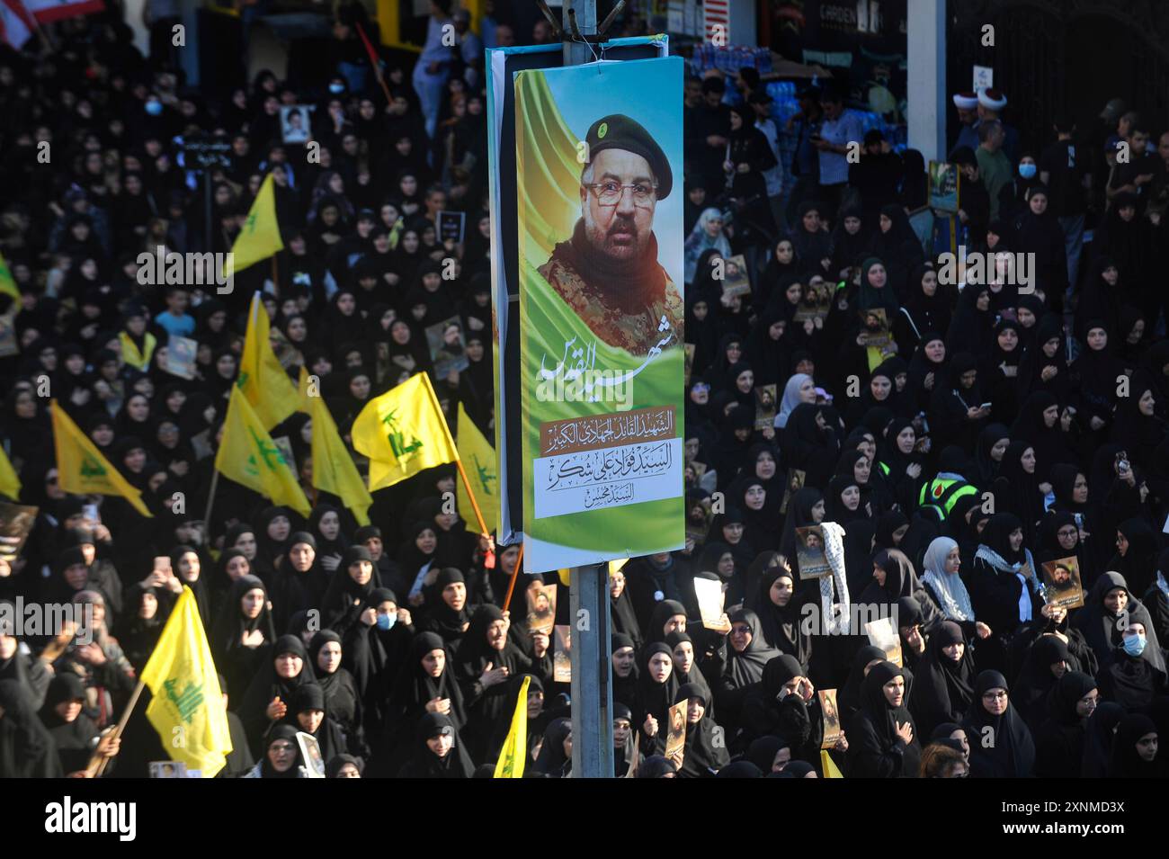 Mourners pass under a giant poster that show the top Hezbollah ...