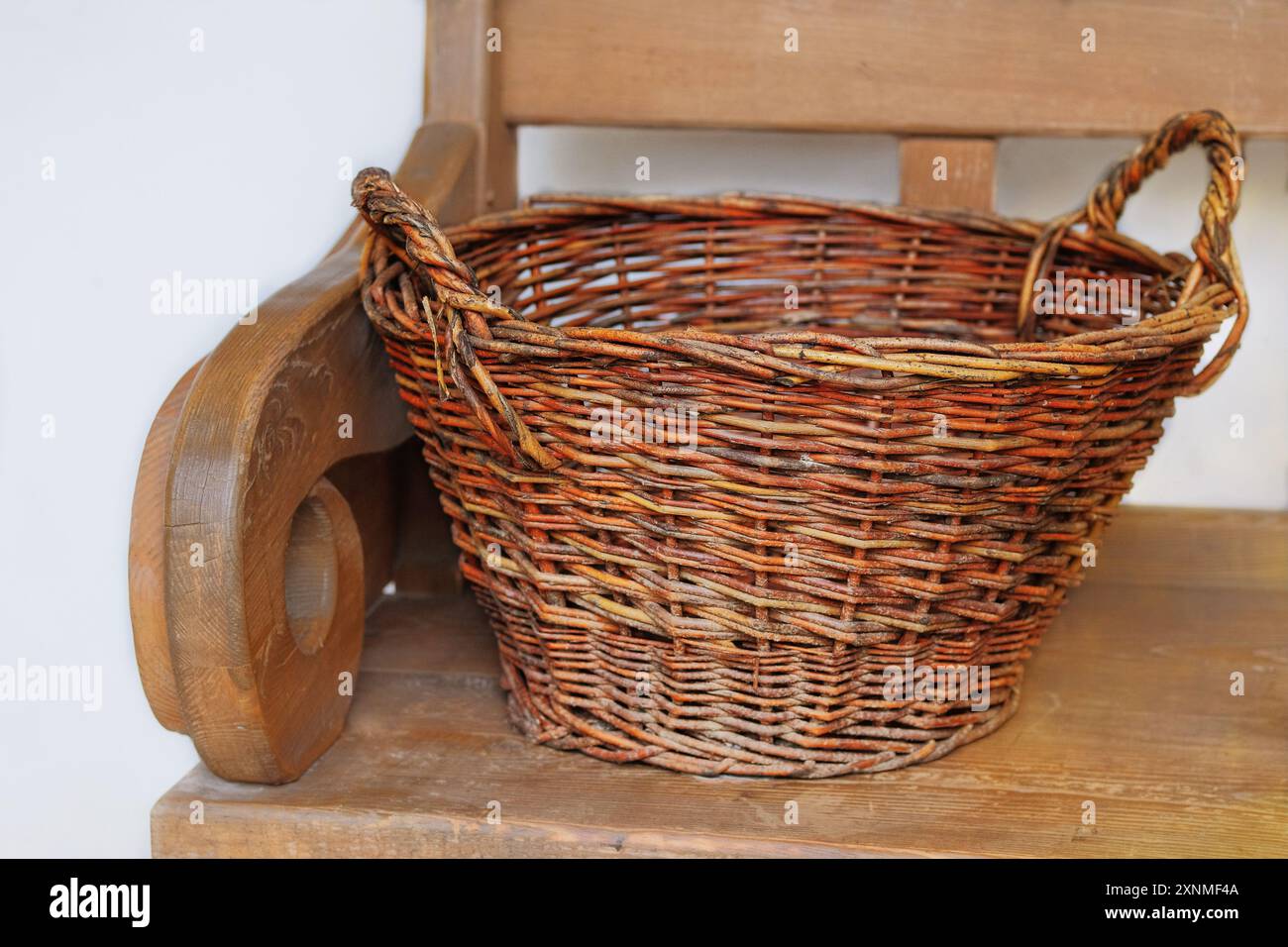 Old wicker basket on a wooden bench. Straw basket in cottage kitchen ...