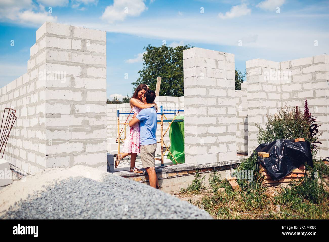 Happy young couple hugging in front of their future house under ...