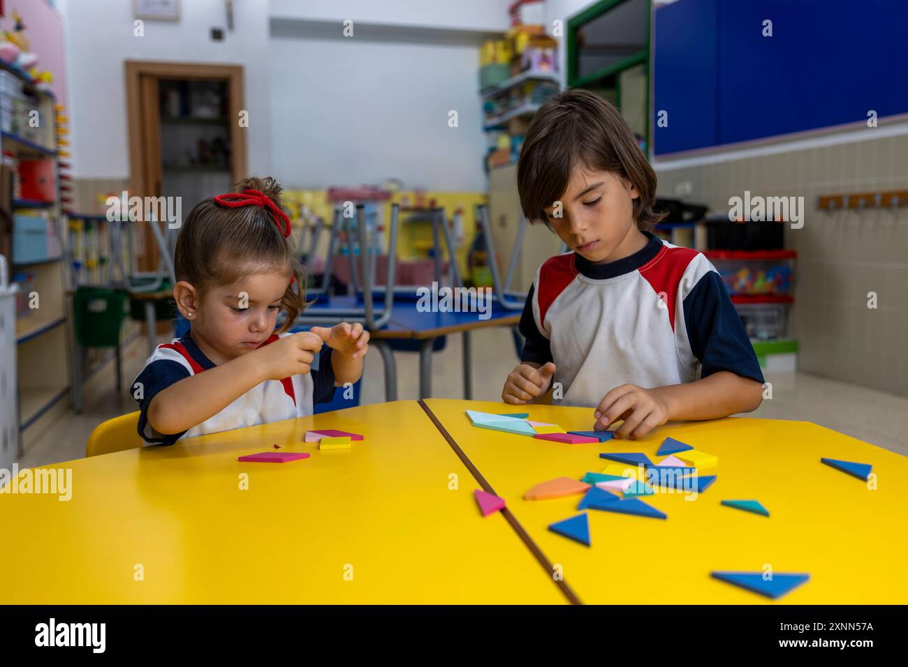Children in kindergarten doing puzzles at the desk Stock Photo - Alamy