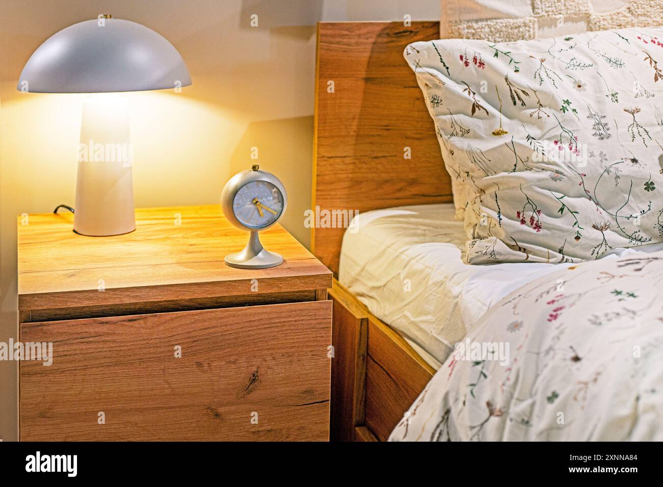 alarm clock is on the bedside table next to the bed. good morning, mode ...