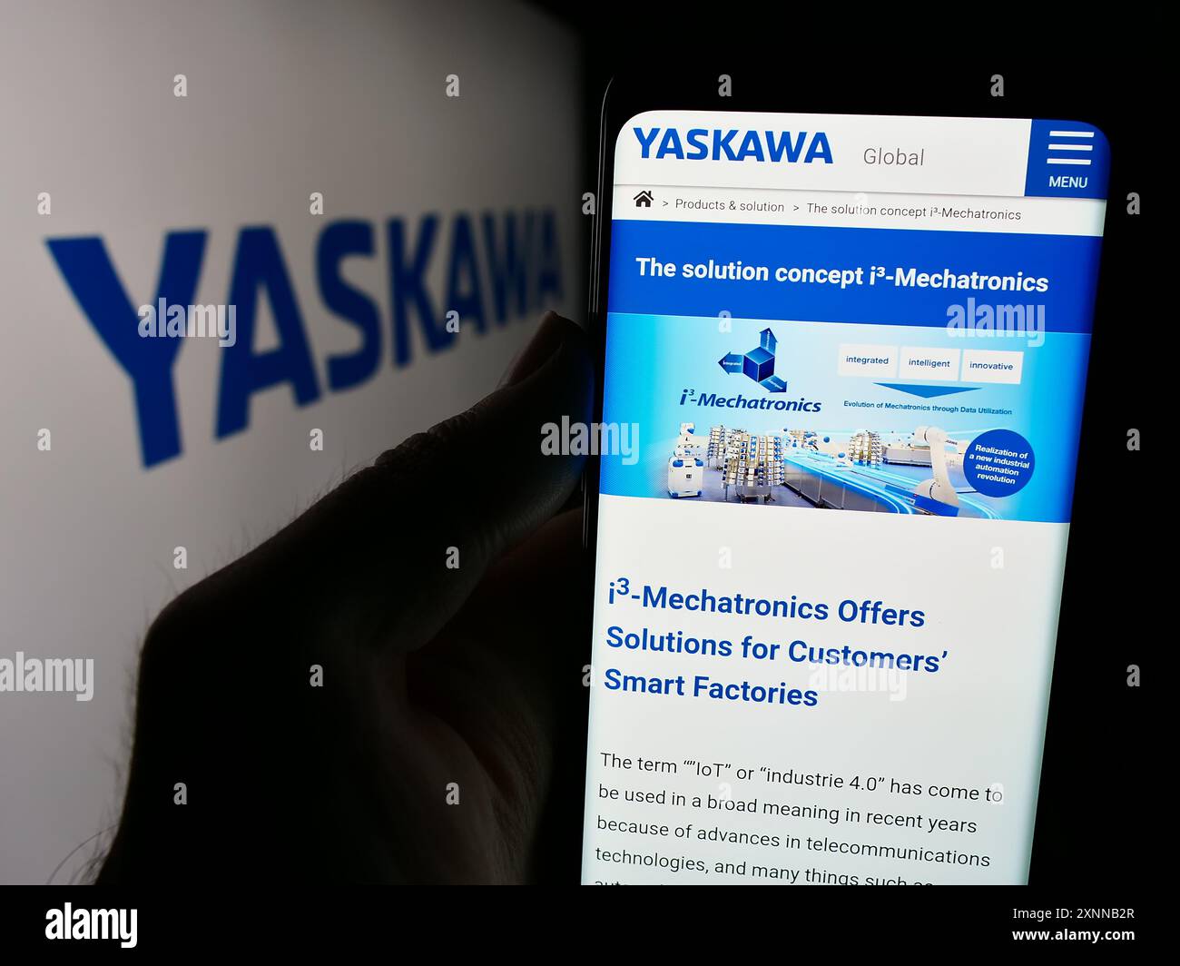 Person holding smartphone with website of Japanese company Yaskawa ...