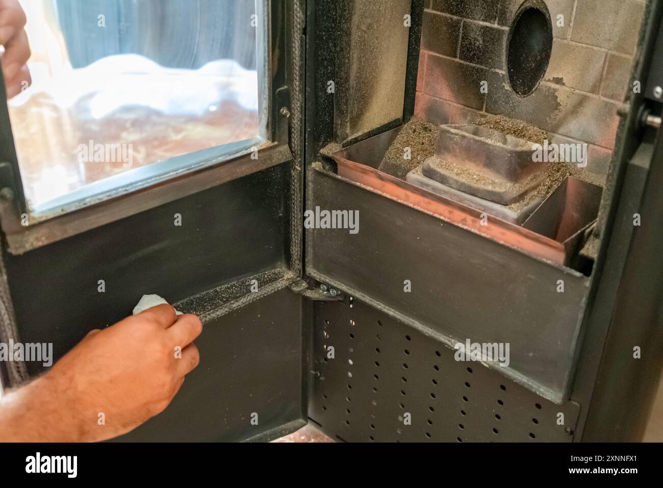 Close-up of a man cleaning the soot produced by the pellet stove in his ...