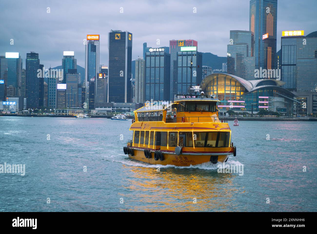 Yellow tourist cruise boat sailing on Victoria Harbour at dusk with the ...
