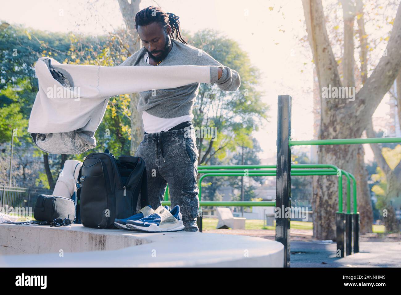 Young African Man standing in the park in the morning, he is changing ...