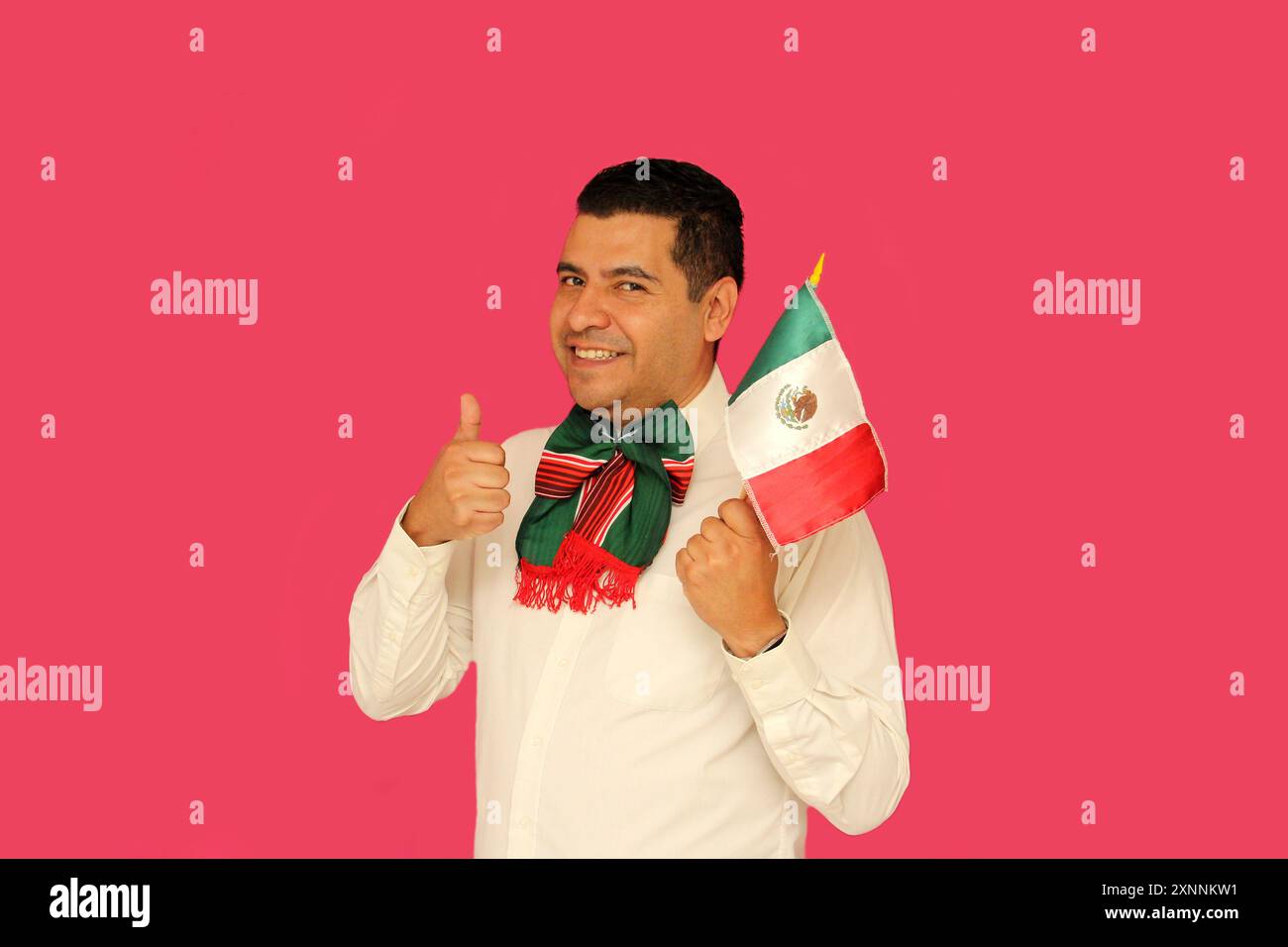 Dark-skinned Mexican adult man with tricolor bow proudly shows the flag ...