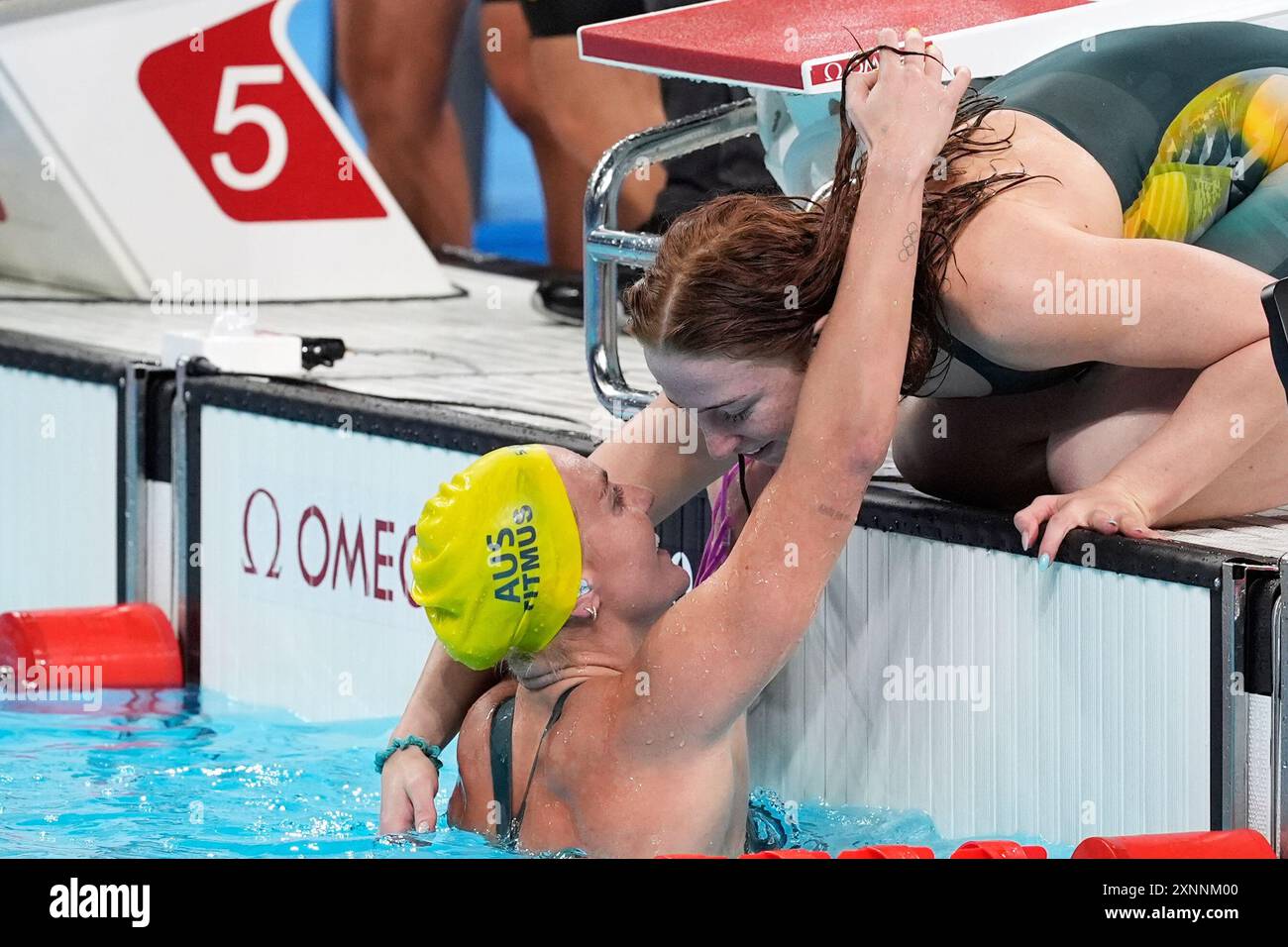 Australia's Ariarne Titmus, left, gets a hug from a teammate after anchoring their team to ...