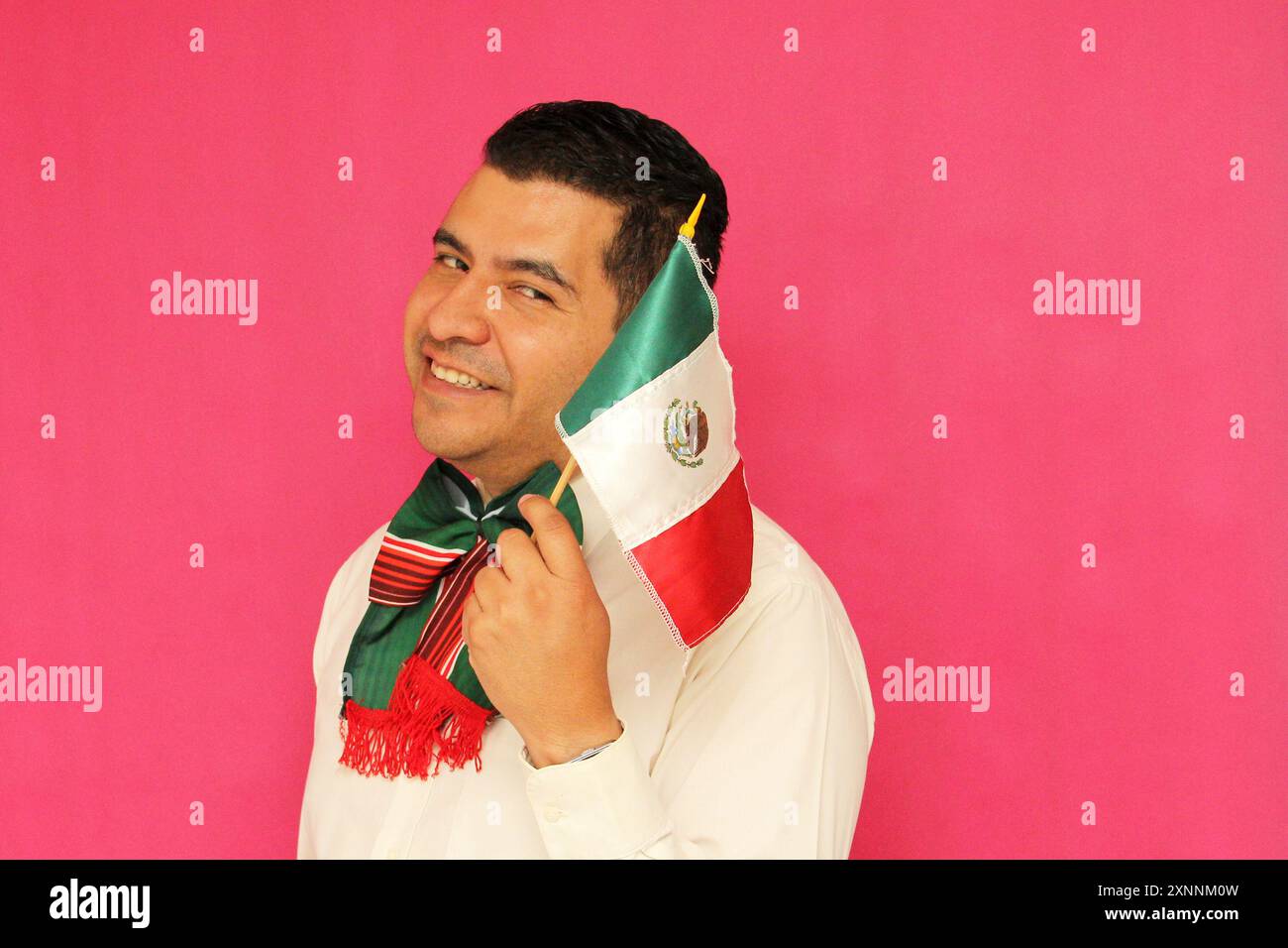 Dark-skinned Mexican adult man with tricolor bow proudly shows the flag ...