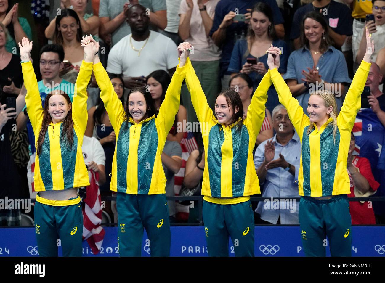 The Australian women's 4x200-meter freestyle relay team raise their arms in unison as they stand ...