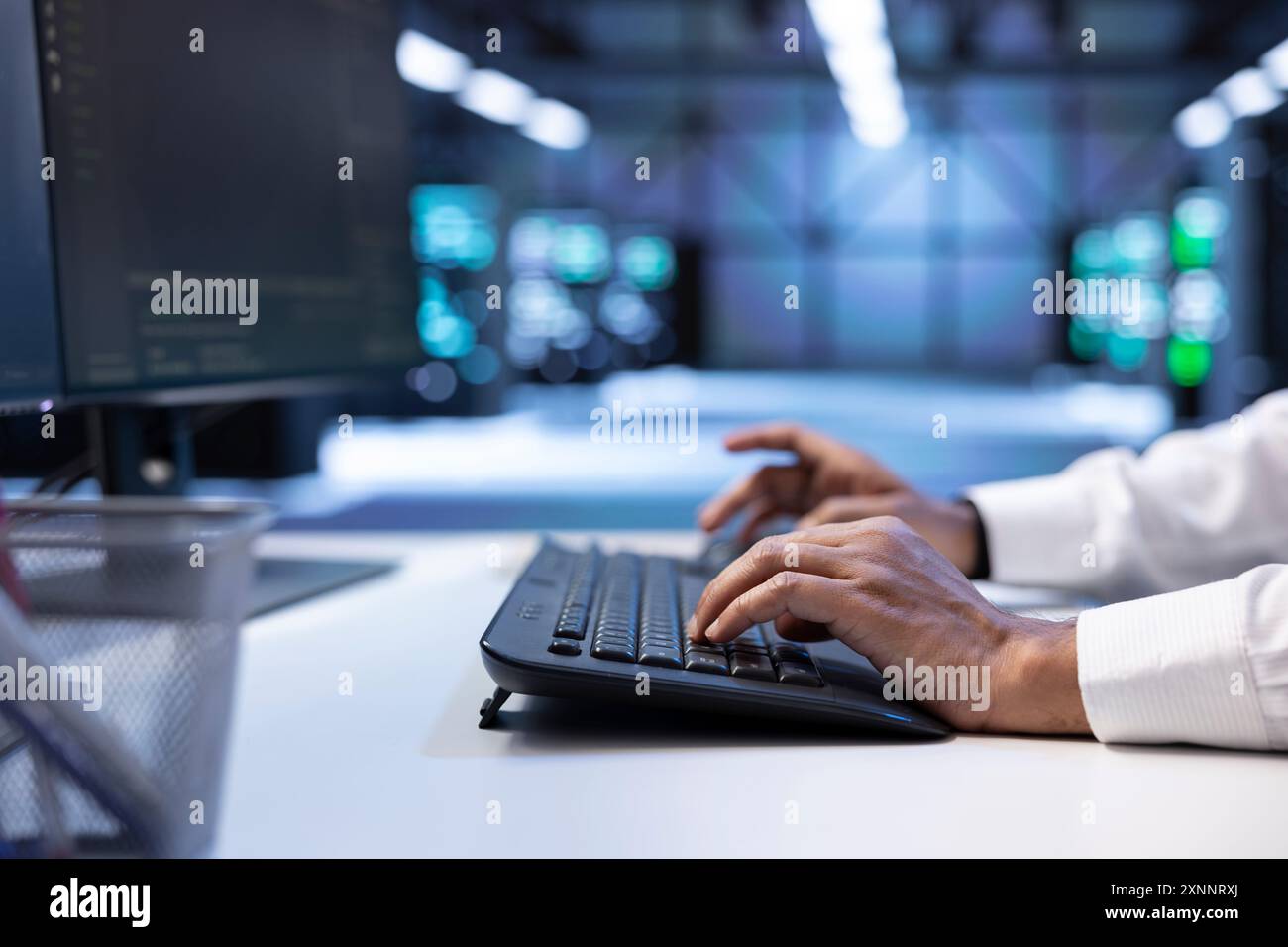 Programmer typing on keyboard, optimizing data center performance and capacity using computer ...
