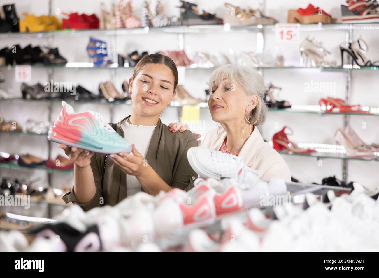 Two female customers choosing fashionable sneakers in shoe store Stock ...