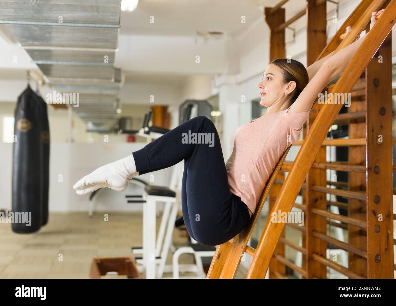 Young woman performing leg raises on wall bars in gym Stock Photo - Alamy