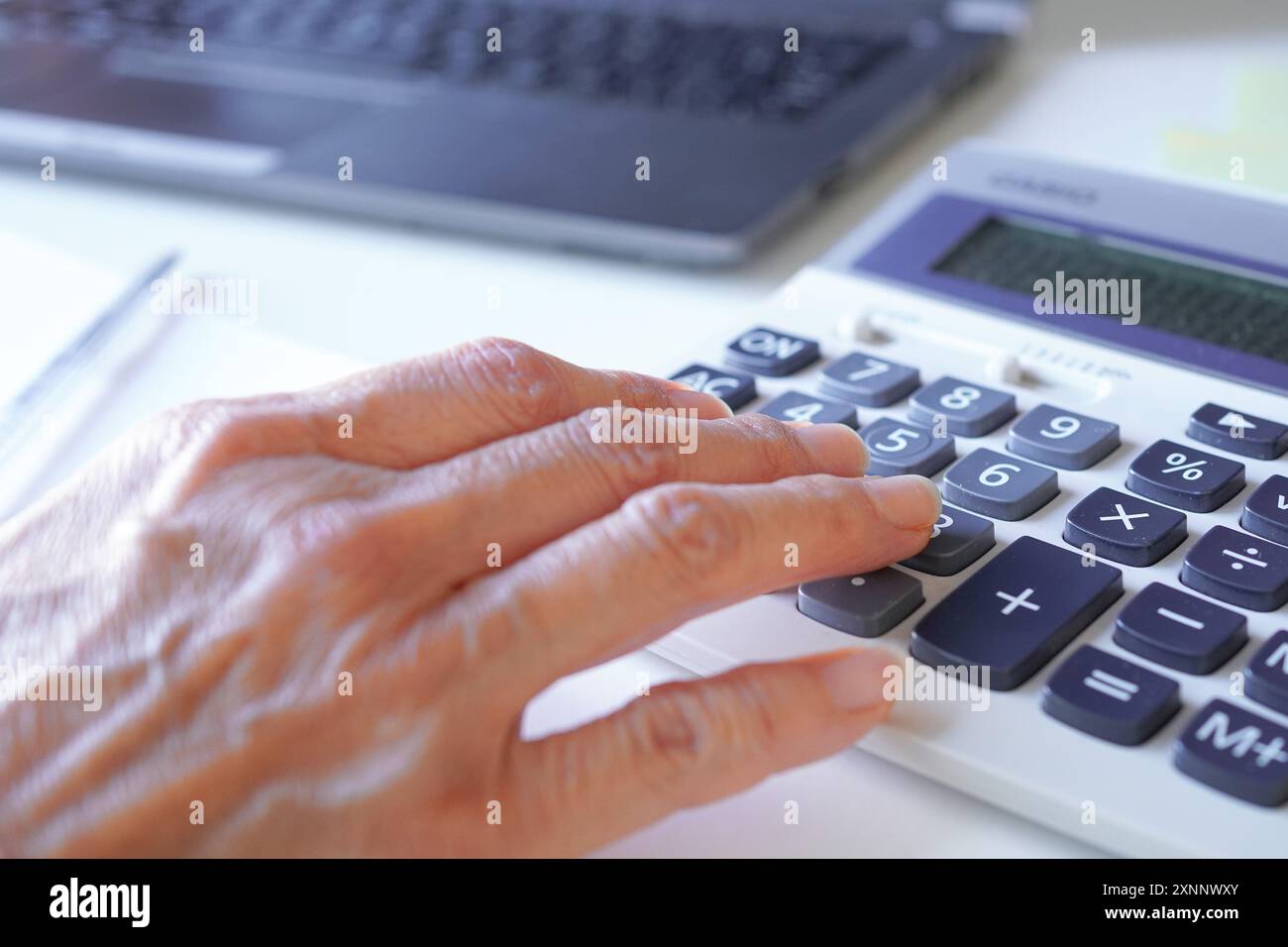 The hand of an older female consultant doing calculations on a ...