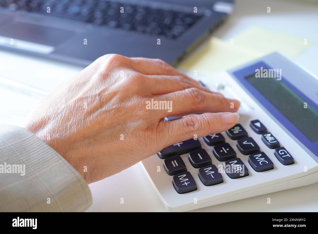 The hand of an older female consultant doing calculations on a ...