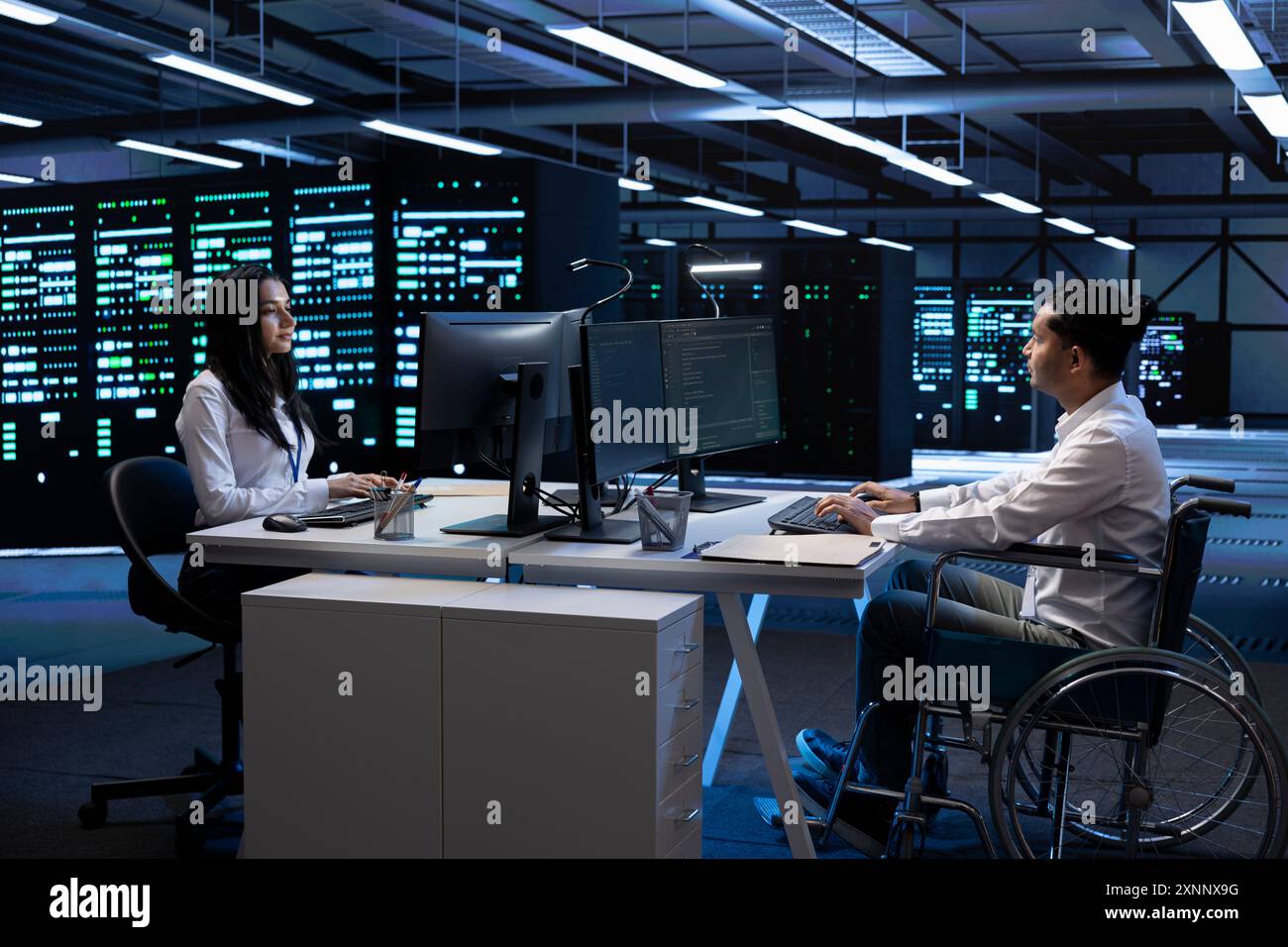 Person with paraplegia and colleague working in inclusive server hub workspace, typing on PC ...