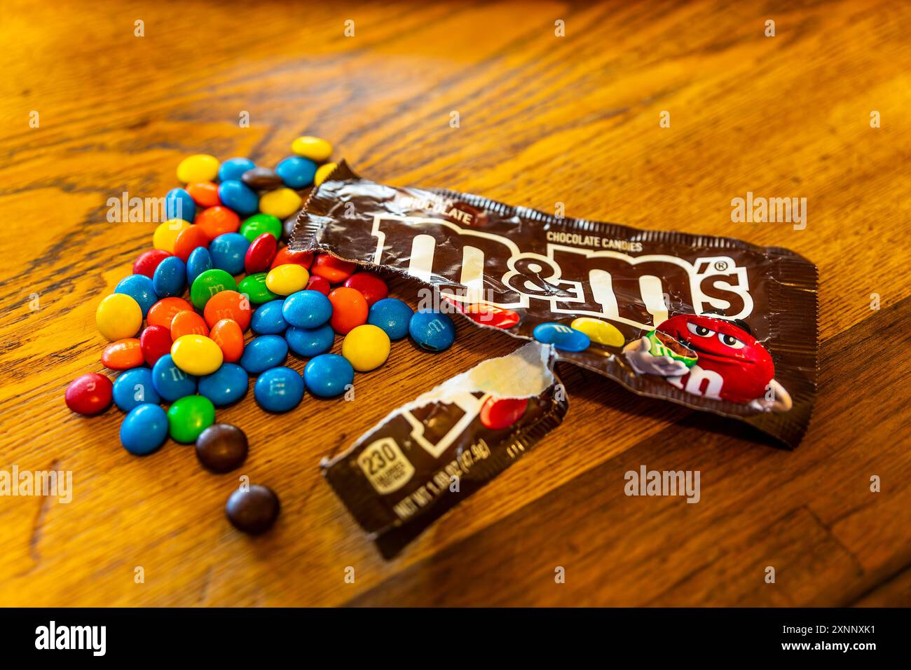 A torn open bag of M and M candies spread on an antique desk Stock Photo - Alamy
