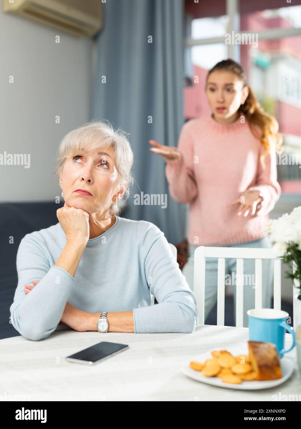 Offended elderly woman listening her daughter swearing Stock Photo - Alamy