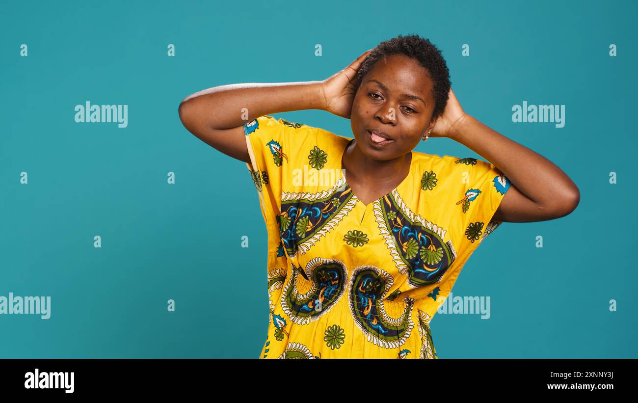 Playful cute girl sticking tongue out and fooling around in studio ...
