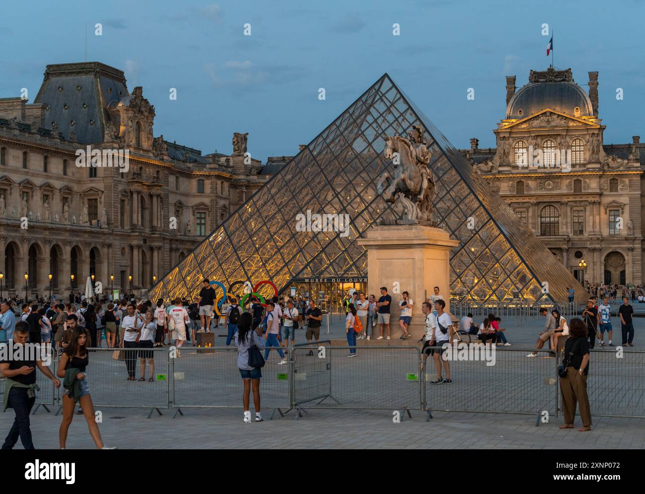Paris, France - July 29, 2024: Evening crowds at the Louvre Glass ...