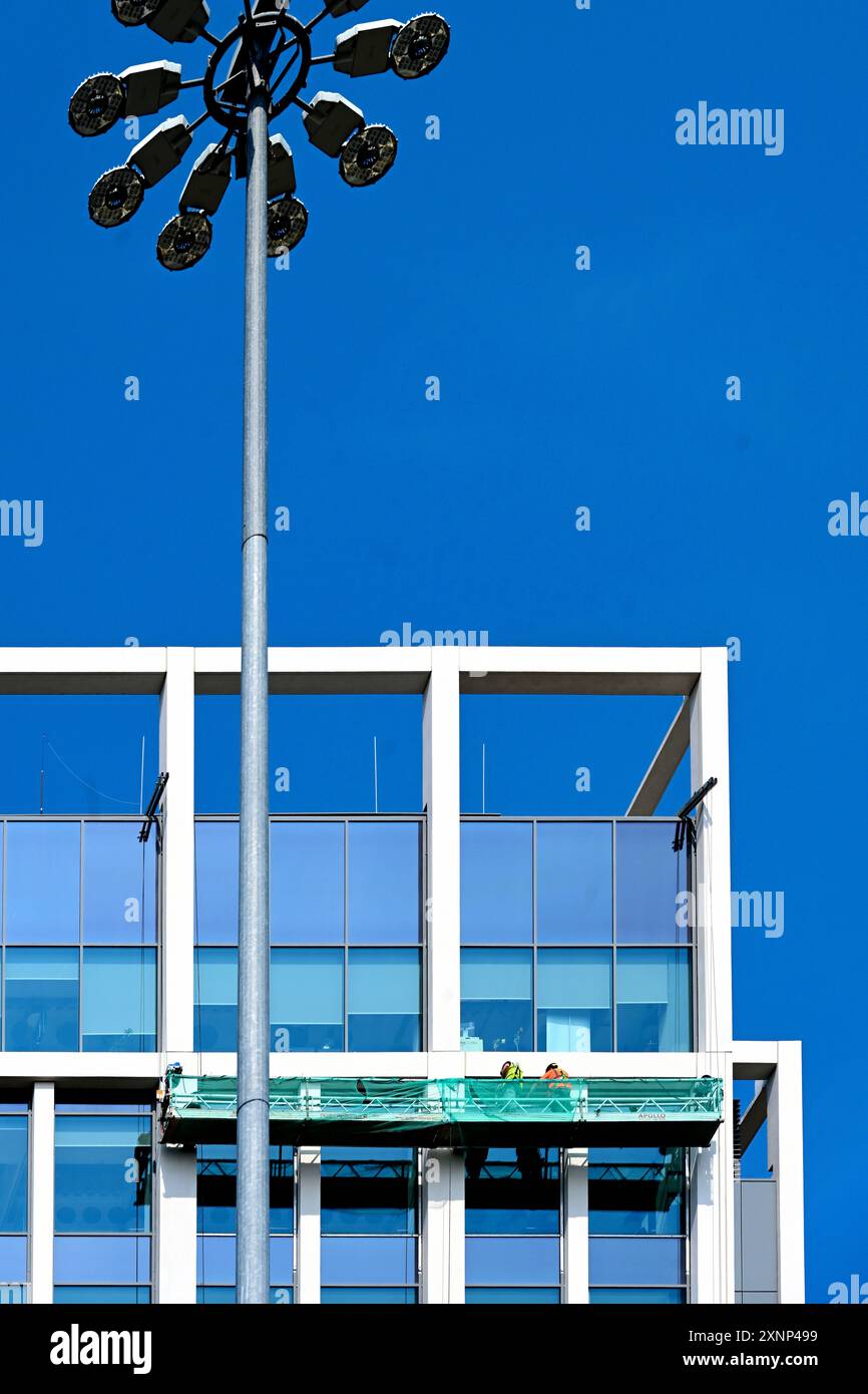 Tower block window cleaning with massive street light and deep blue sky ...