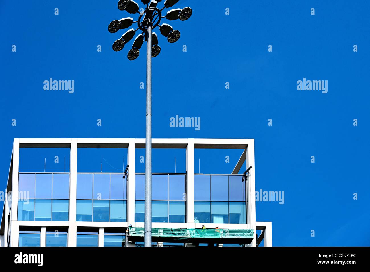 Tower block window cleaning with massive street light and deep blue sky ...