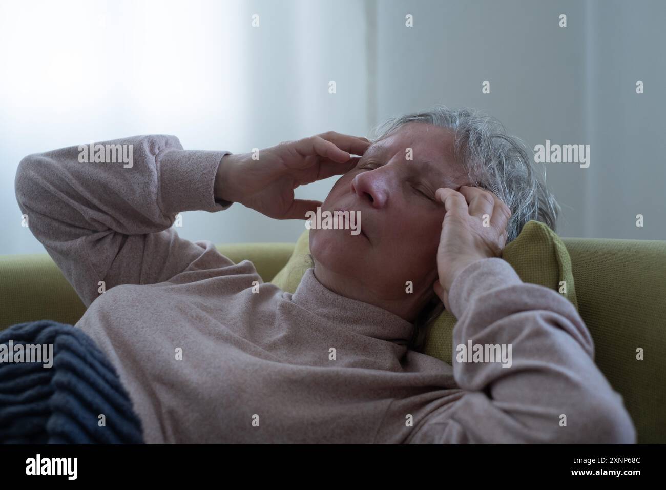 A sick old woman laying down in bed and having migraine Stock Photo - Alamy