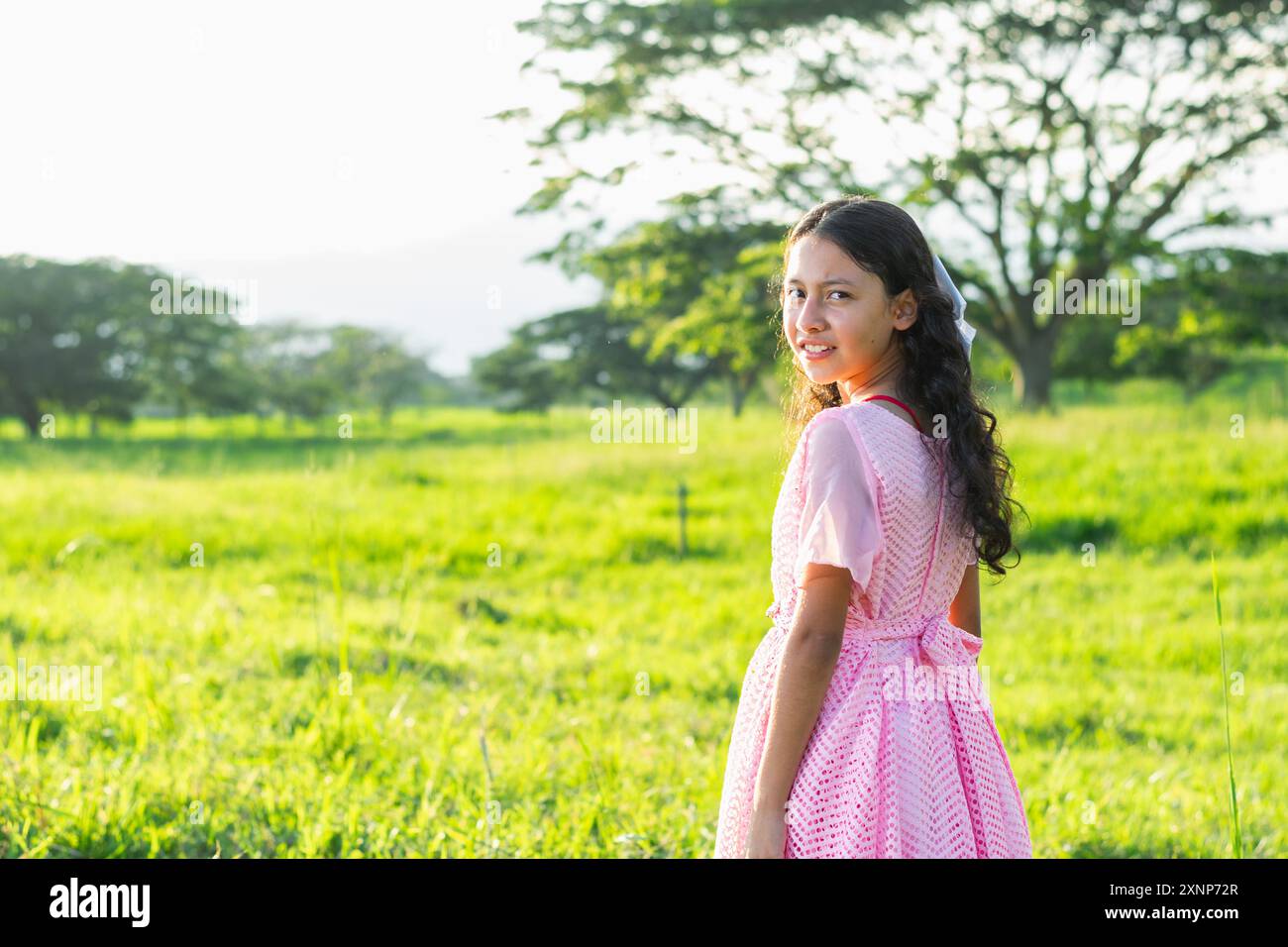 little brunette latina girl walking through a field of green grass ...