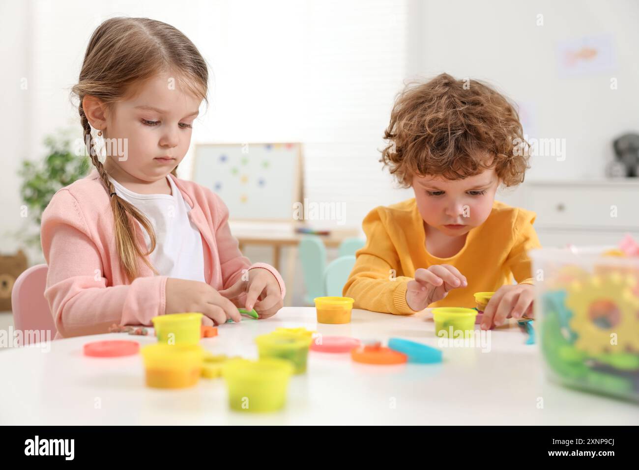 Cute little children modeling from plasticine at white table in ...