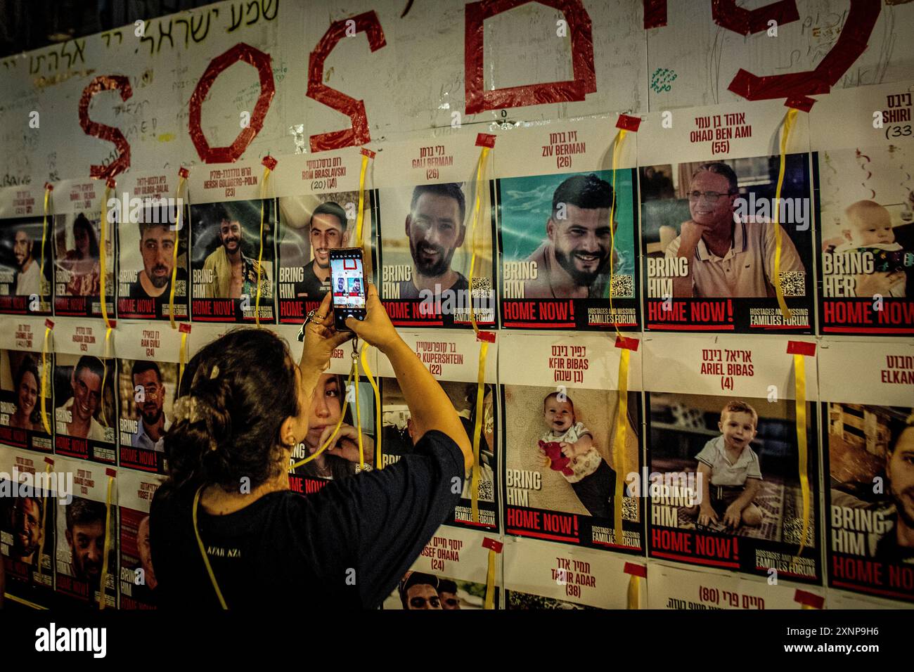 An Israeli woman photographs a billboard covered with images of ...