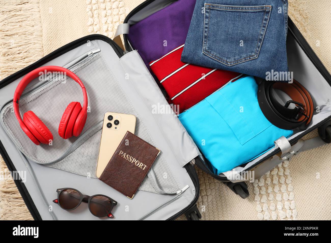 Open suitcase with traveler's belongings on floor, top view Stock Photo ...