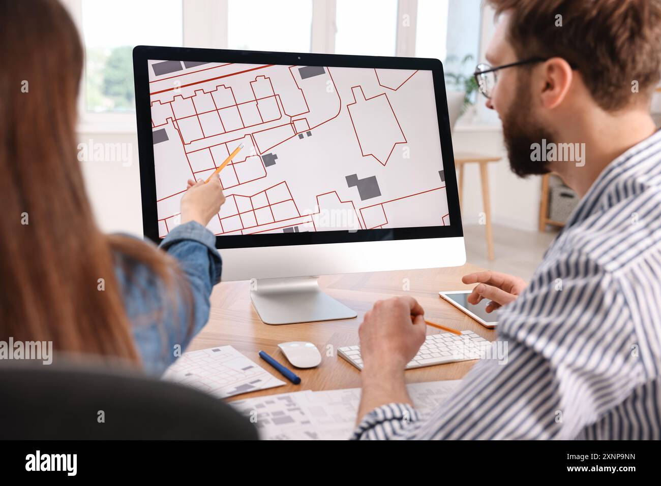 Cartographers working with cadastral map on computer at table in office ...