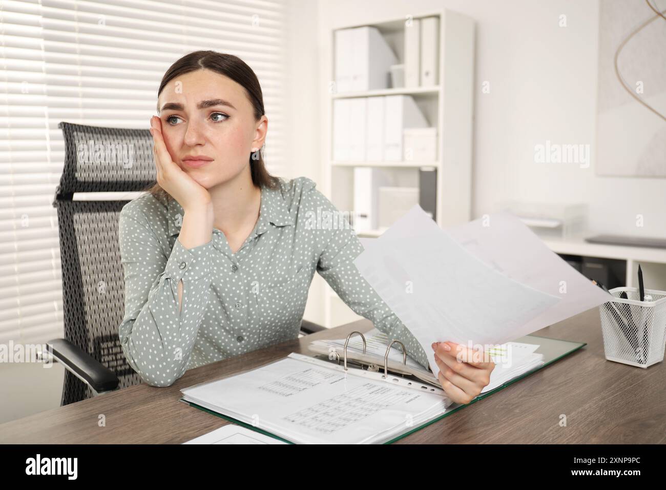 Embarrassed woman with documents at wooden table in office Stock Photo ...