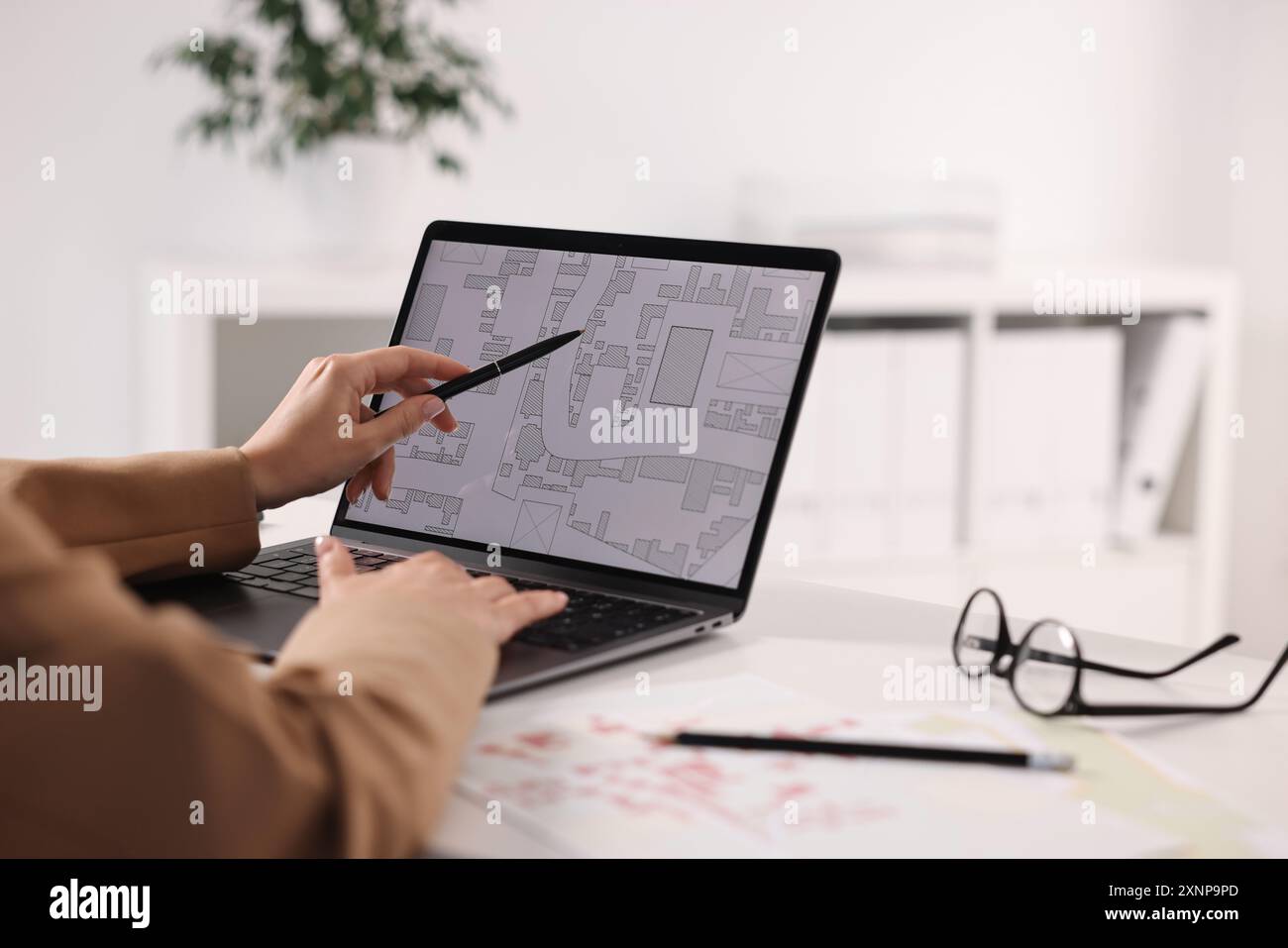 Cartographer working with cadastral map on laptop at white table in ...