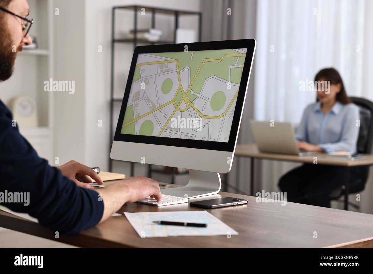 Cartographer working with cadastral map on computer at wooden table in ...
