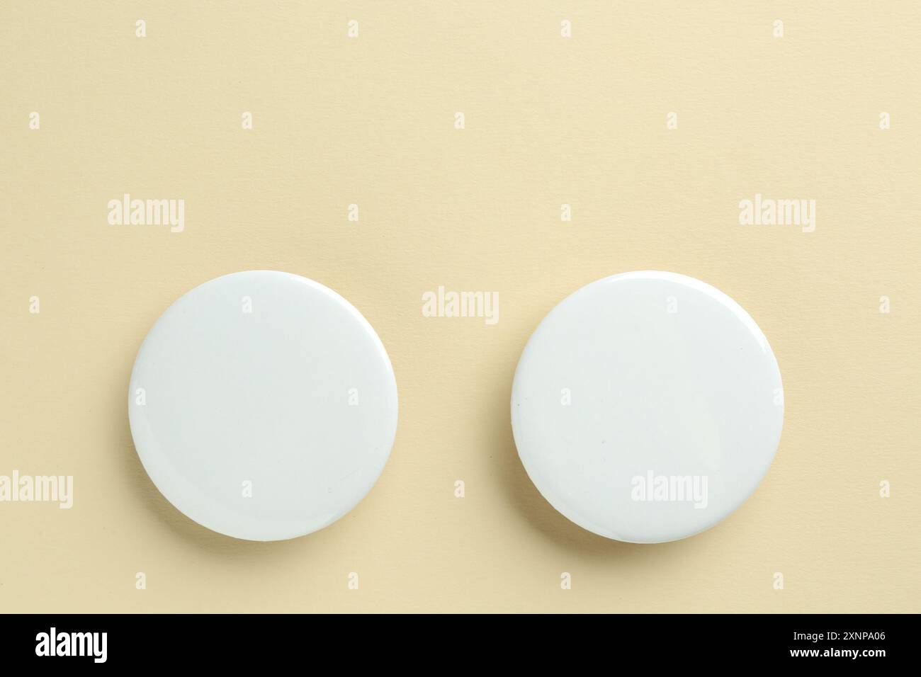 White button badges on beige background, flat lay. Mockup for design ...