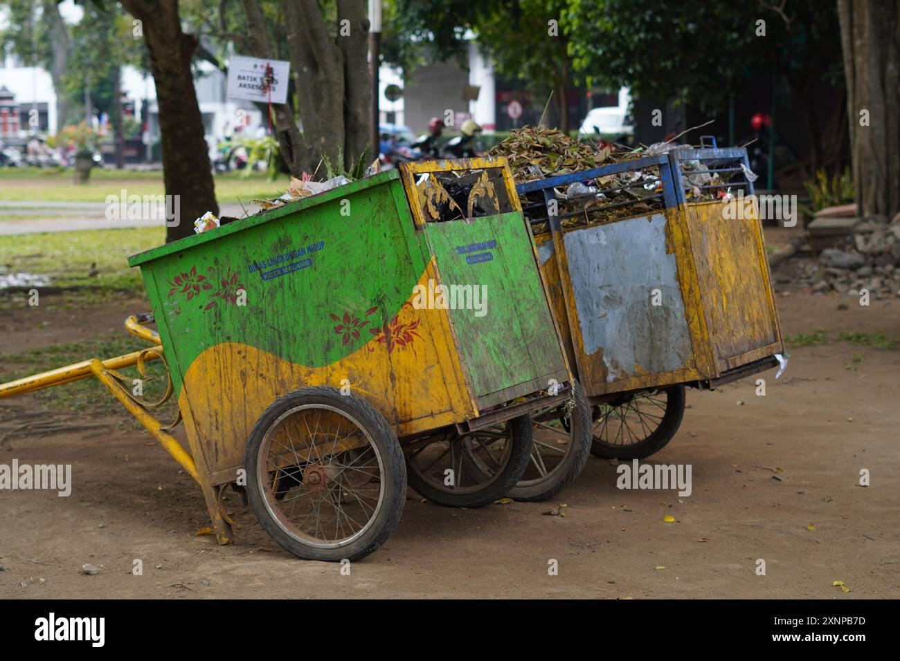 A dirty looking garbage cart filled with garbage in a park Stock Photo ...