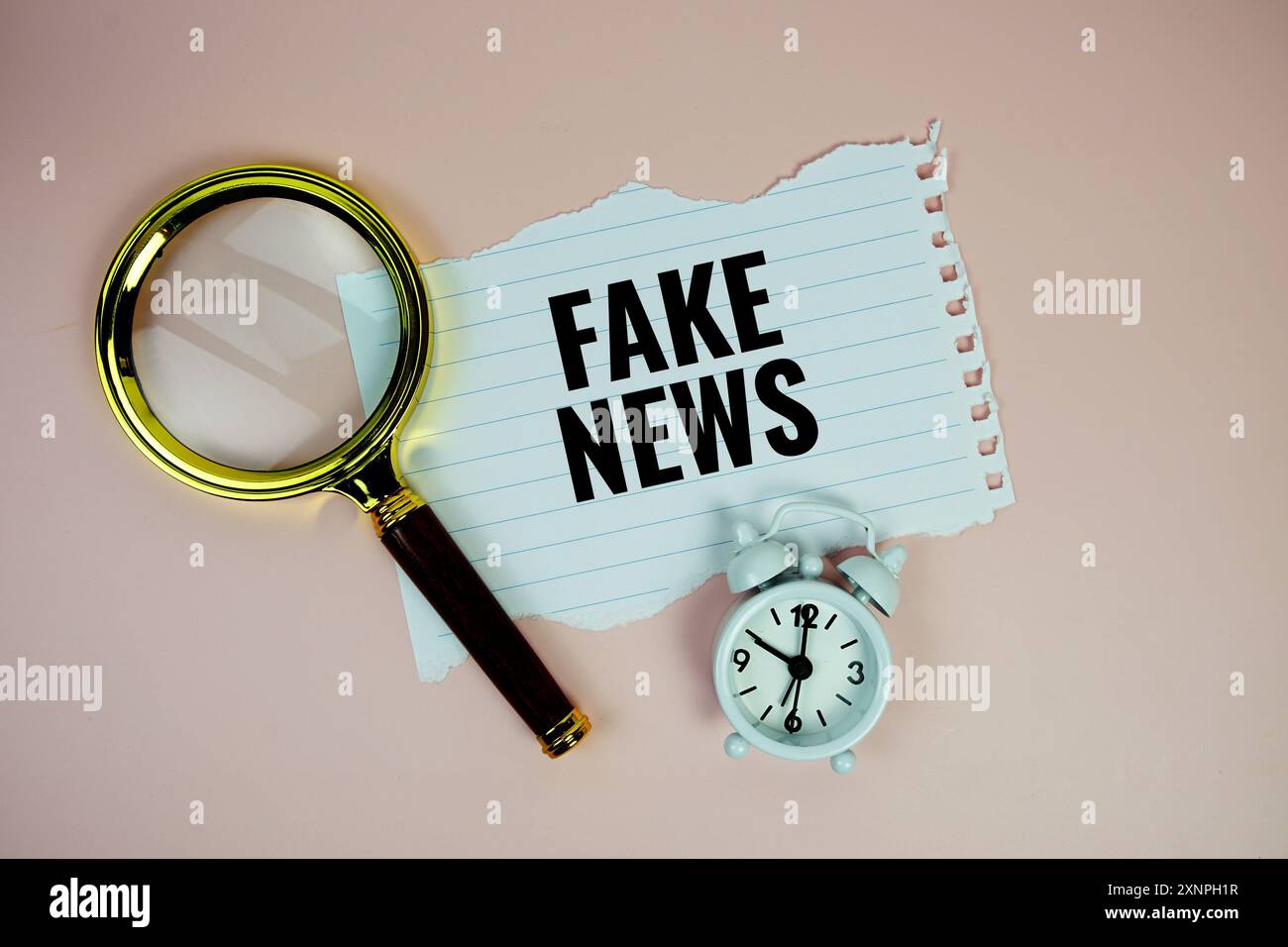 Fake News text on paper torn with alarm clock and magnifying glass top ...