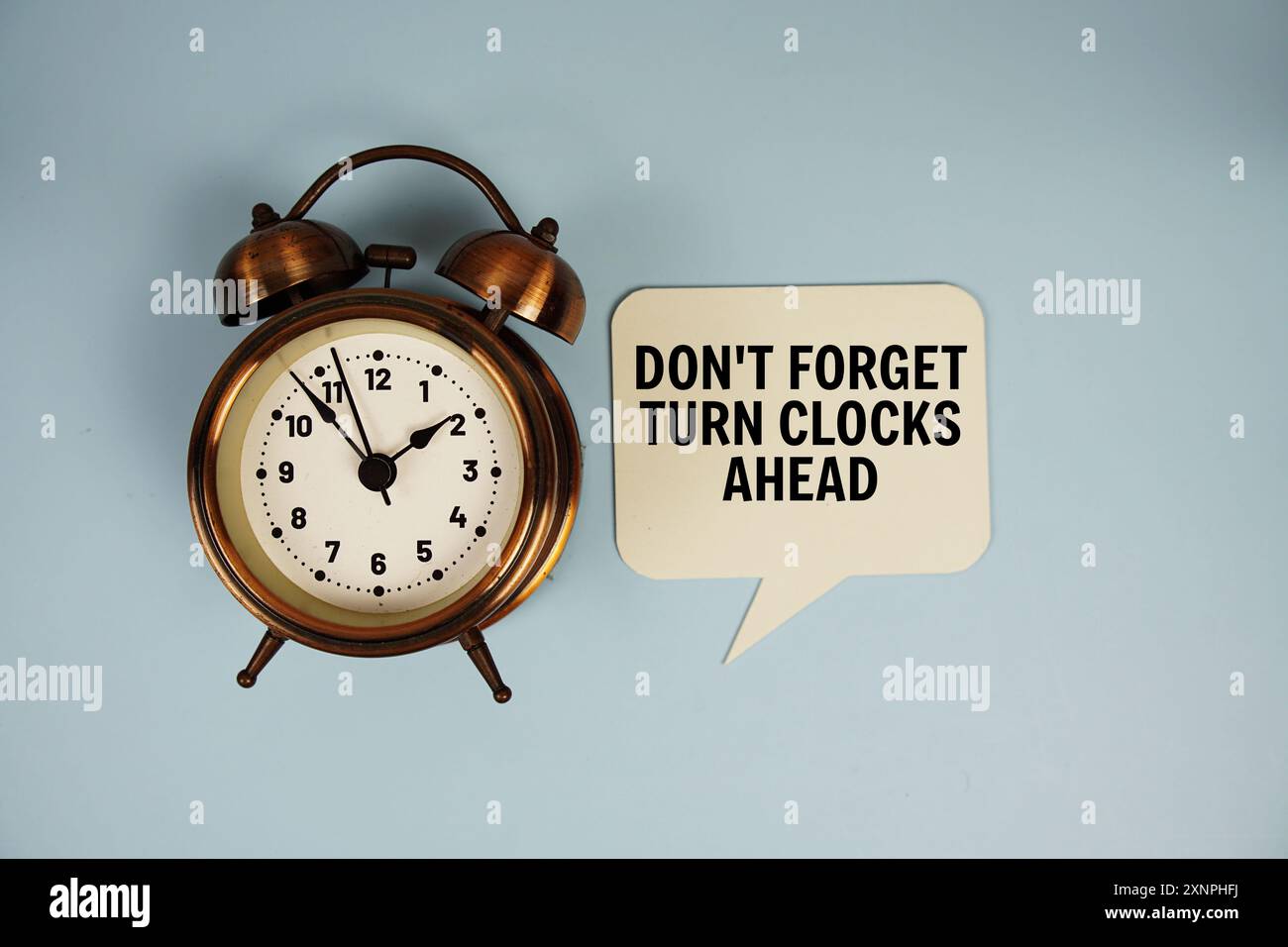 Turn Clocks Ahead text on paper card with alarm clock on blue ...
